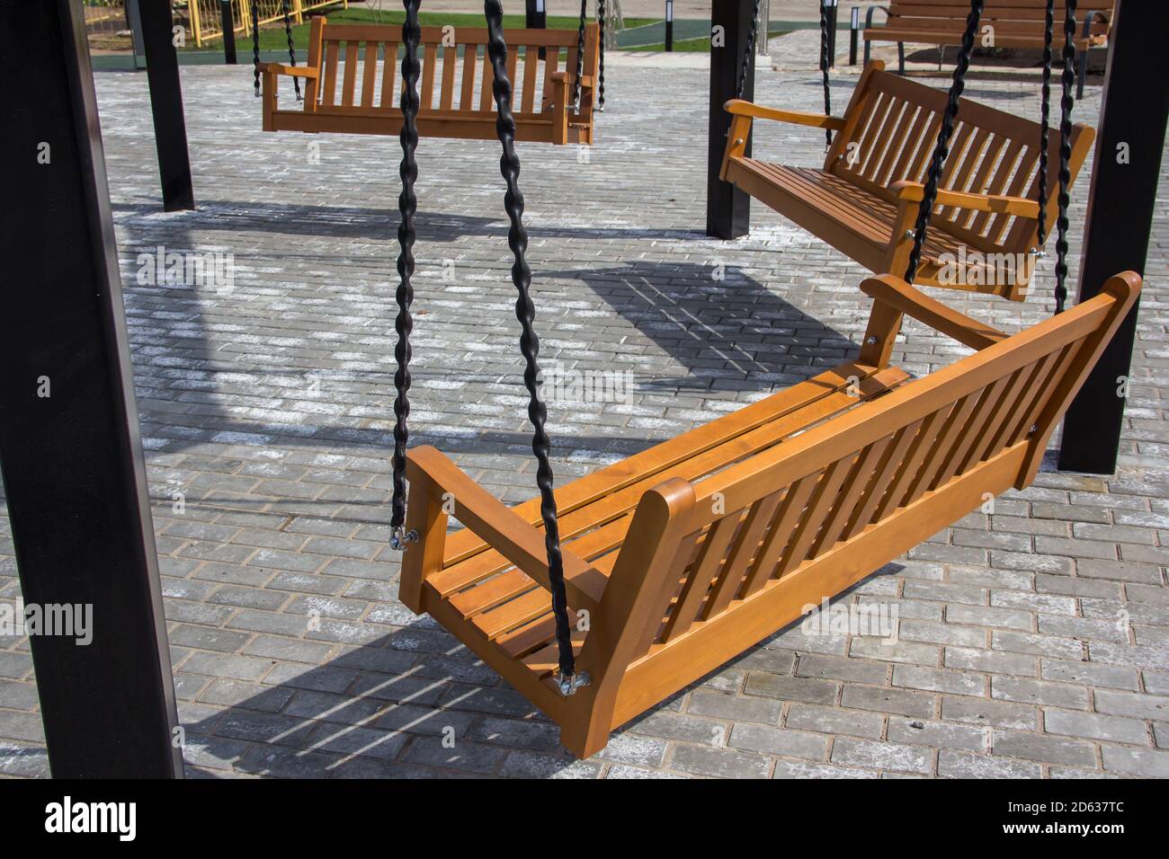 New swing bench in the park. Swing in the form of a wooden park bench ...