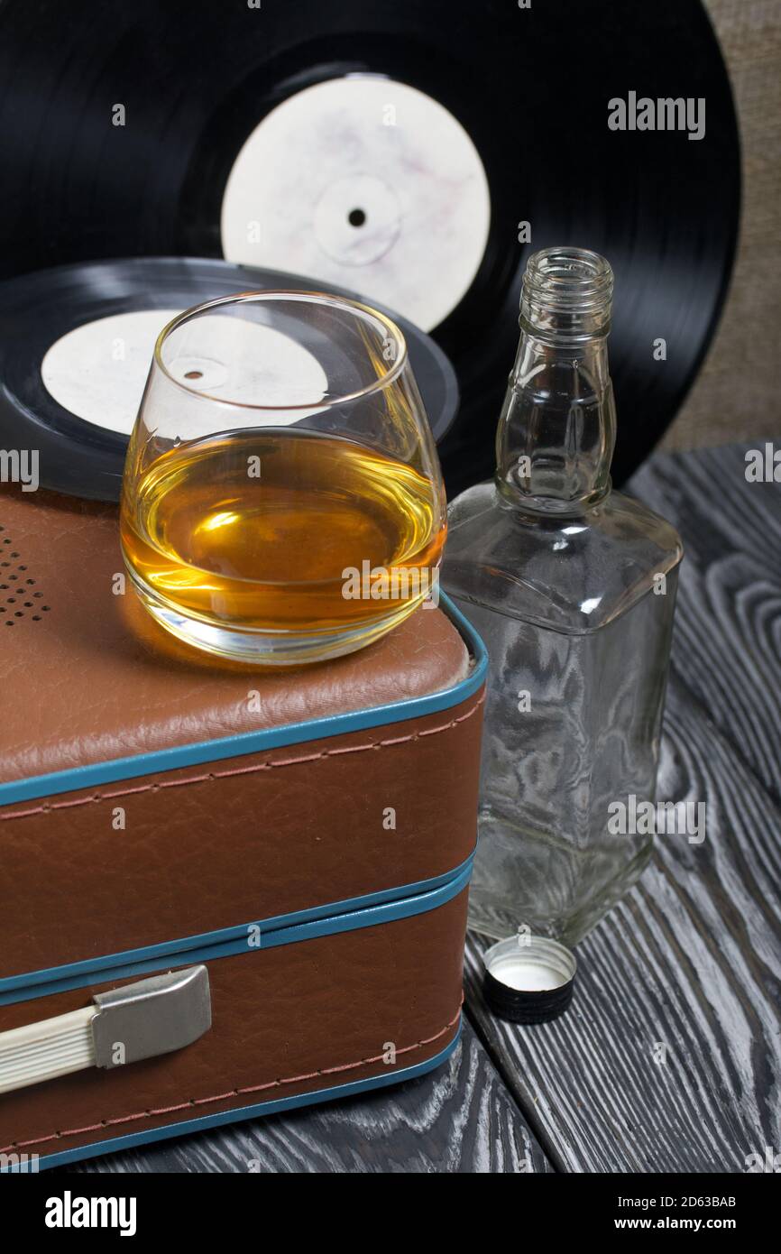 Old record player in the form of a suitcase. Nearby is a glass of ...