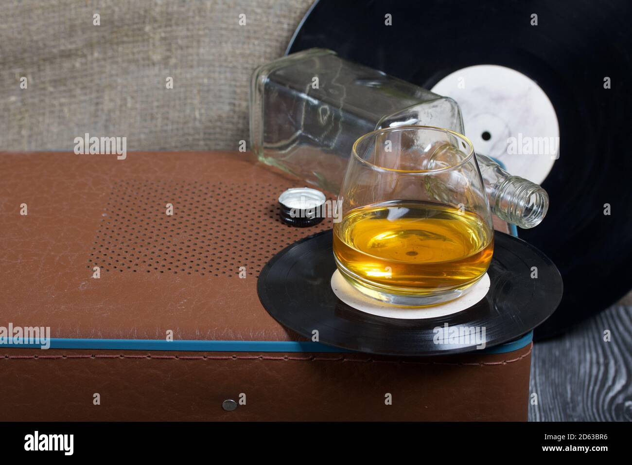 Old record player in the form of a suitcase. Nearby is a glass of ...