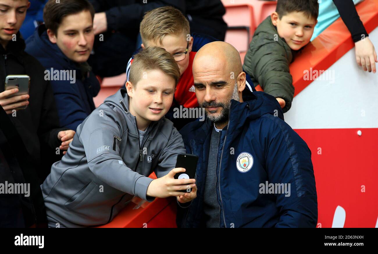 Manchester City manager Pep Guardiola (right) takes a selfie with a ...