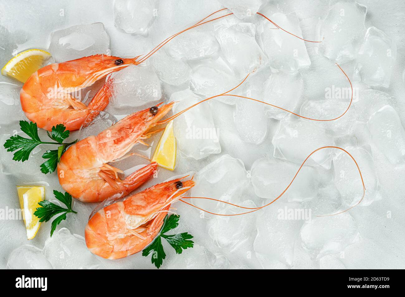Tiger prawns on ice background with lemon and parsley. Flat lay, copy ...