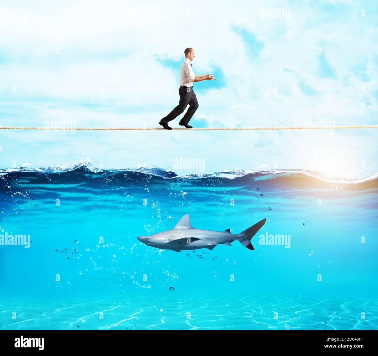Worry man in balance walking on a rope over a shark Stock Photo - Alamy