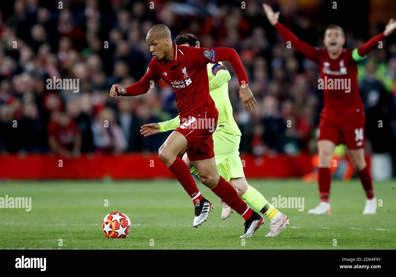 Liverpool's Fabinho (left) and Barcelona's Lionel Messi (back) battle ...