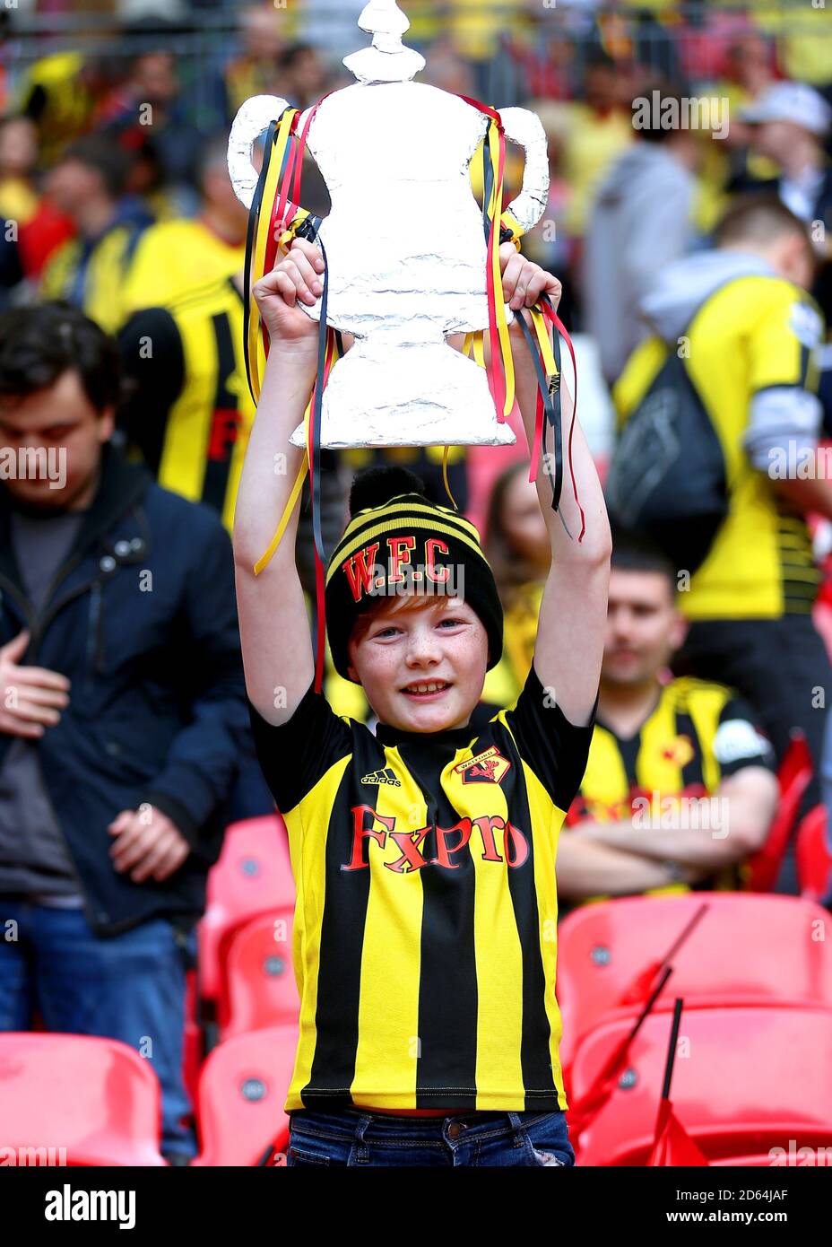 A Watford fan in the stands holds up a replica of the FA Cup trophy ...