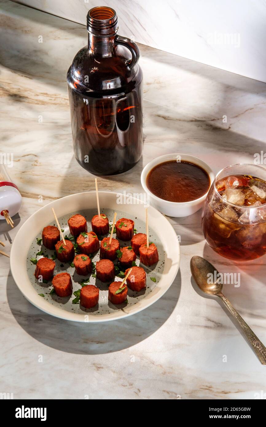 Cocktail hot dogs served with bourbon dipping sauce with glass of ...