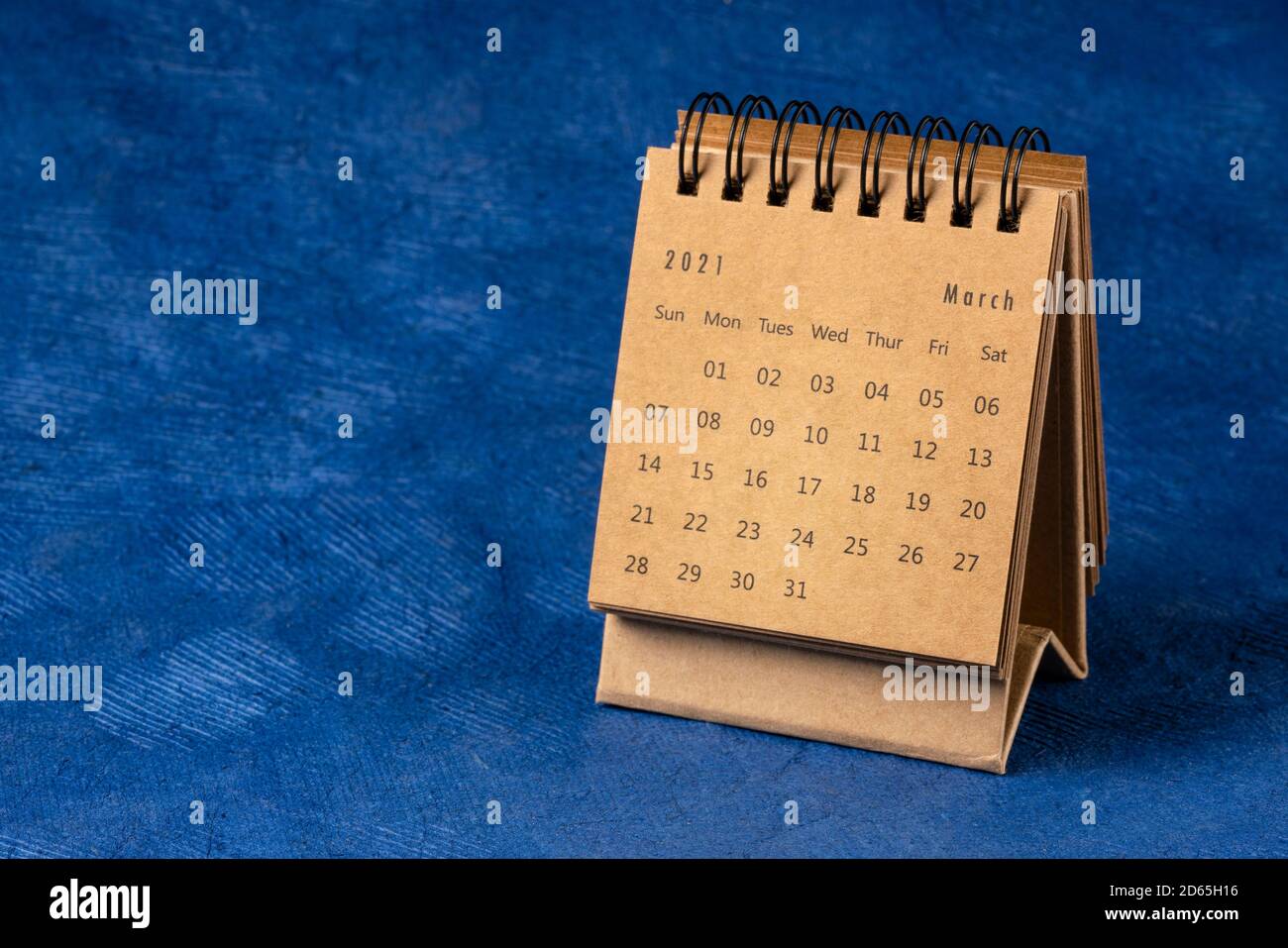 March 2021- spiral desktop calendar against blue handmade paper, time ...