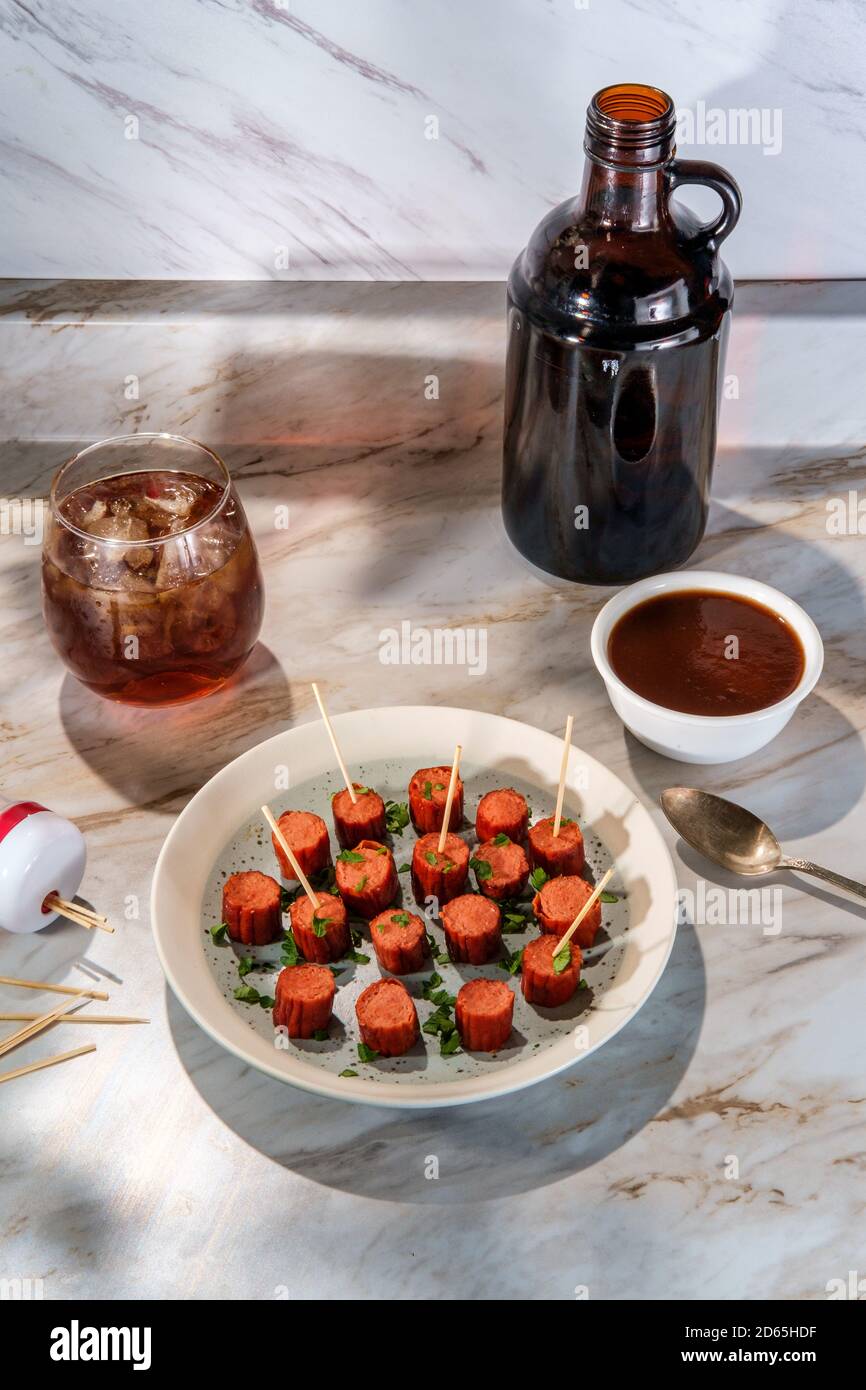 Cocktail hot dogs served with bourbon dipping sauce with glass of ...