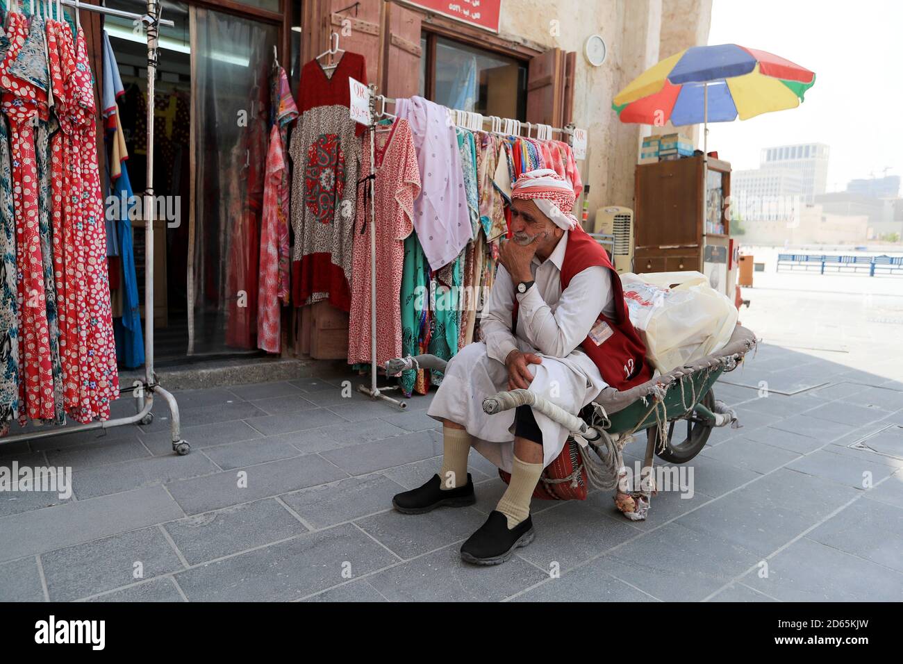 A salesman outside a shop selling fabric and clothes in Doha, Qatar ...