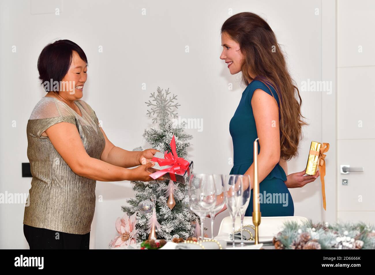 Woman hiding a gift box behind her while receiving another gift box ...
