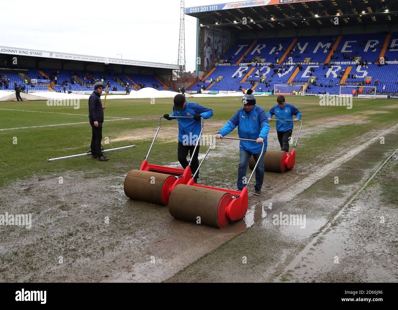 Ground staff members push water off the pitch ahead of the match Stock ...