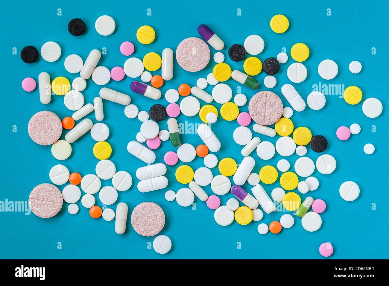 Different kinds of pills in different colors and sizes on a blue ...