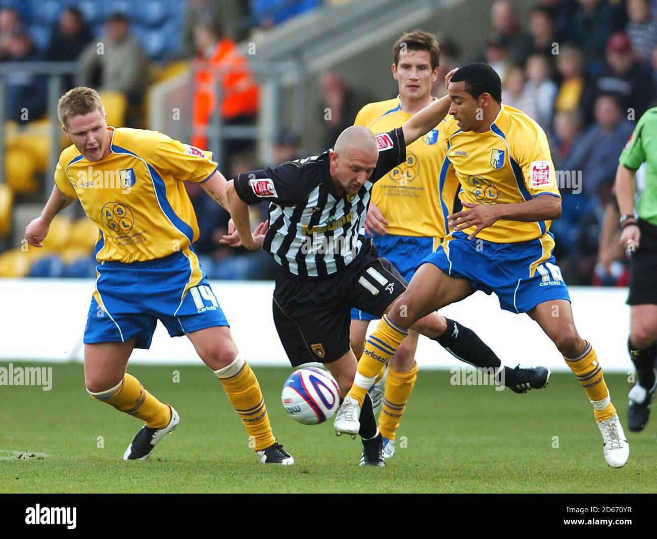 Mansfield Town's Dan Martin and Nathan Arnold try to stop Notts County ...