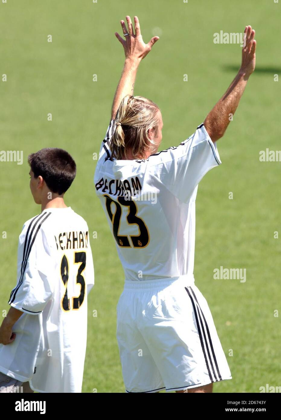 David Beckham signs for Real Madrid as he stands with a young fan who ...