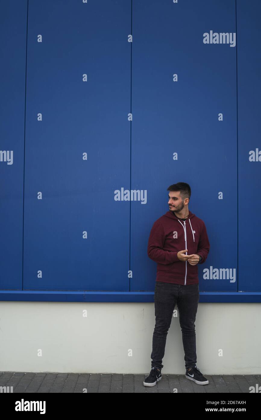 Vertical shot of a male standing by a blue wall Stock Photo - Alamy