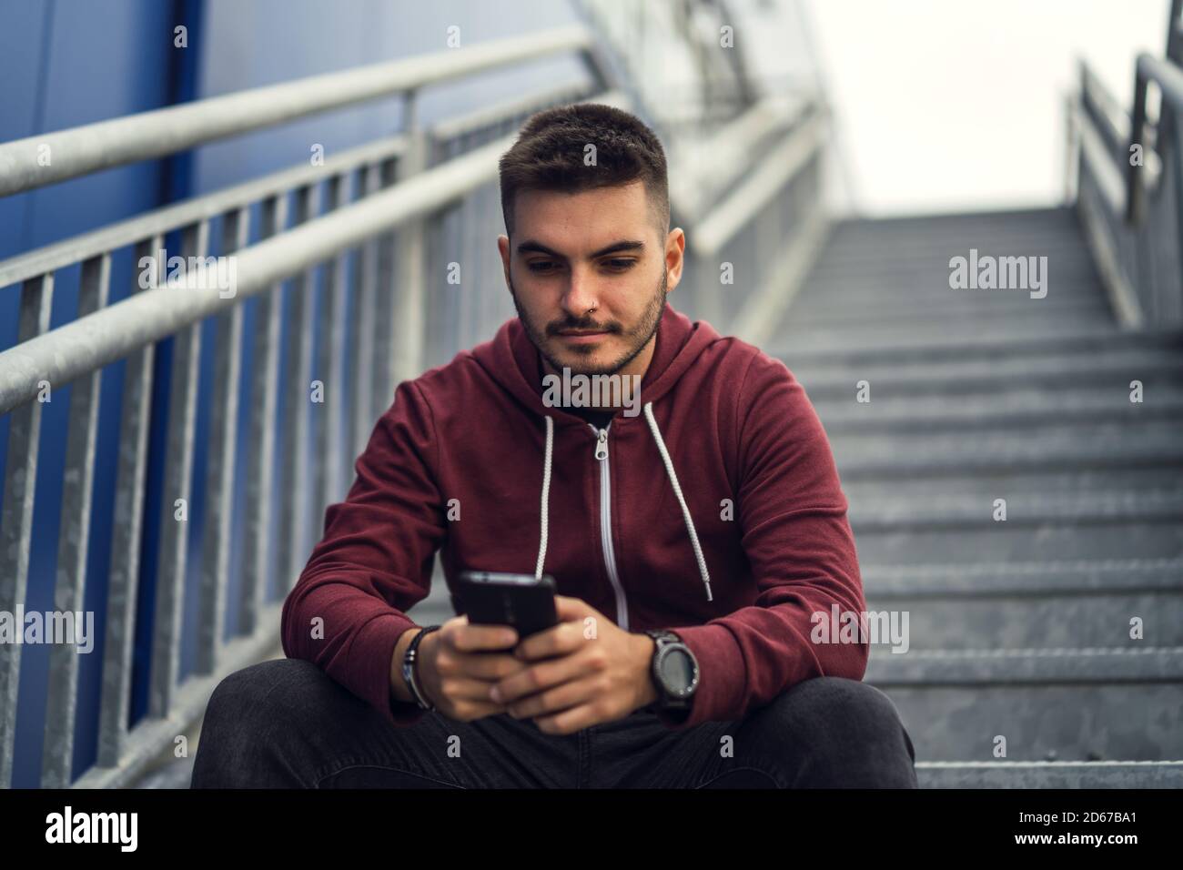Male using his phone while sitting on a staircase Stock Photo - Alamy