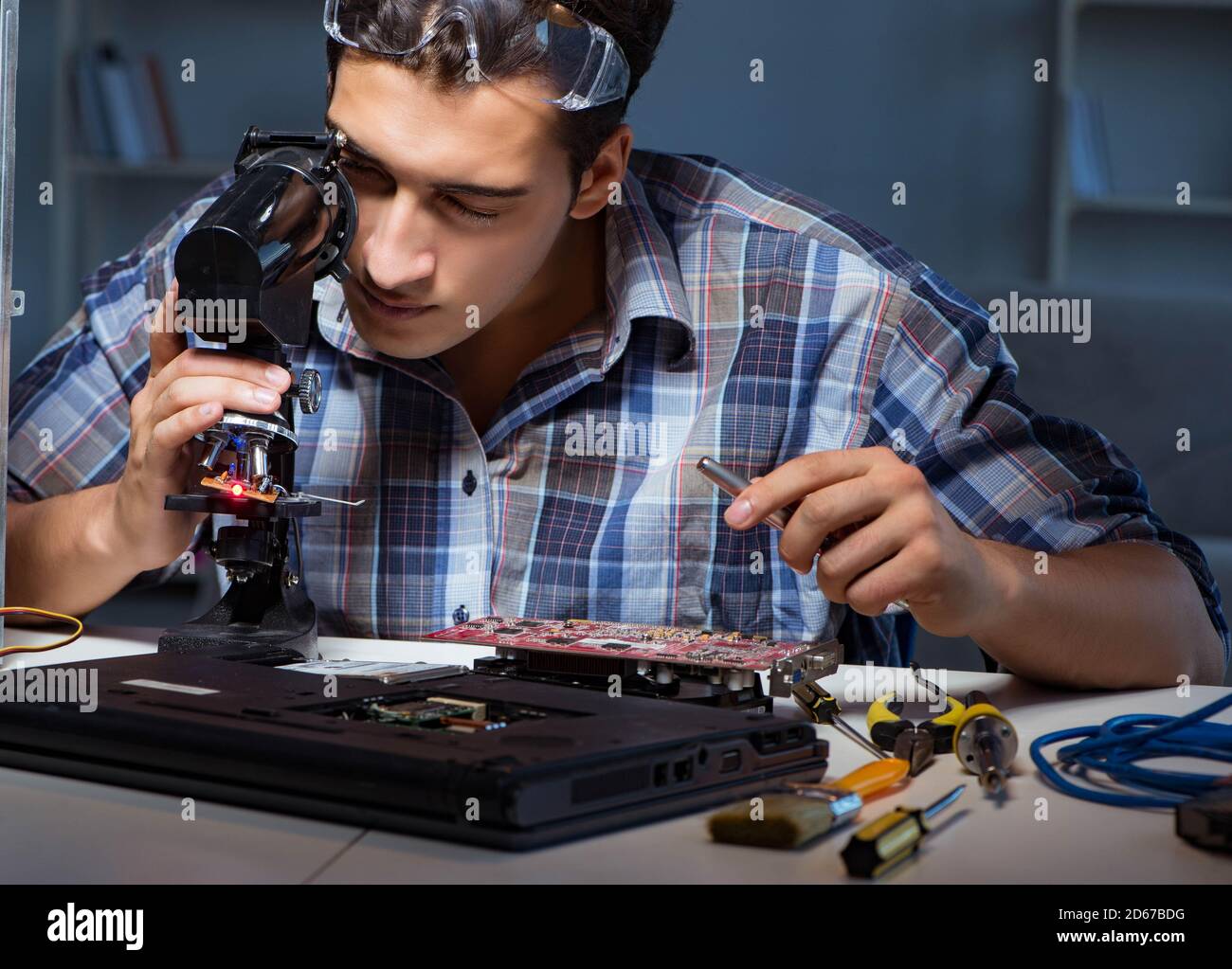 The repairman trying to repair laptop with miscroscope Stock Photo - Alamy