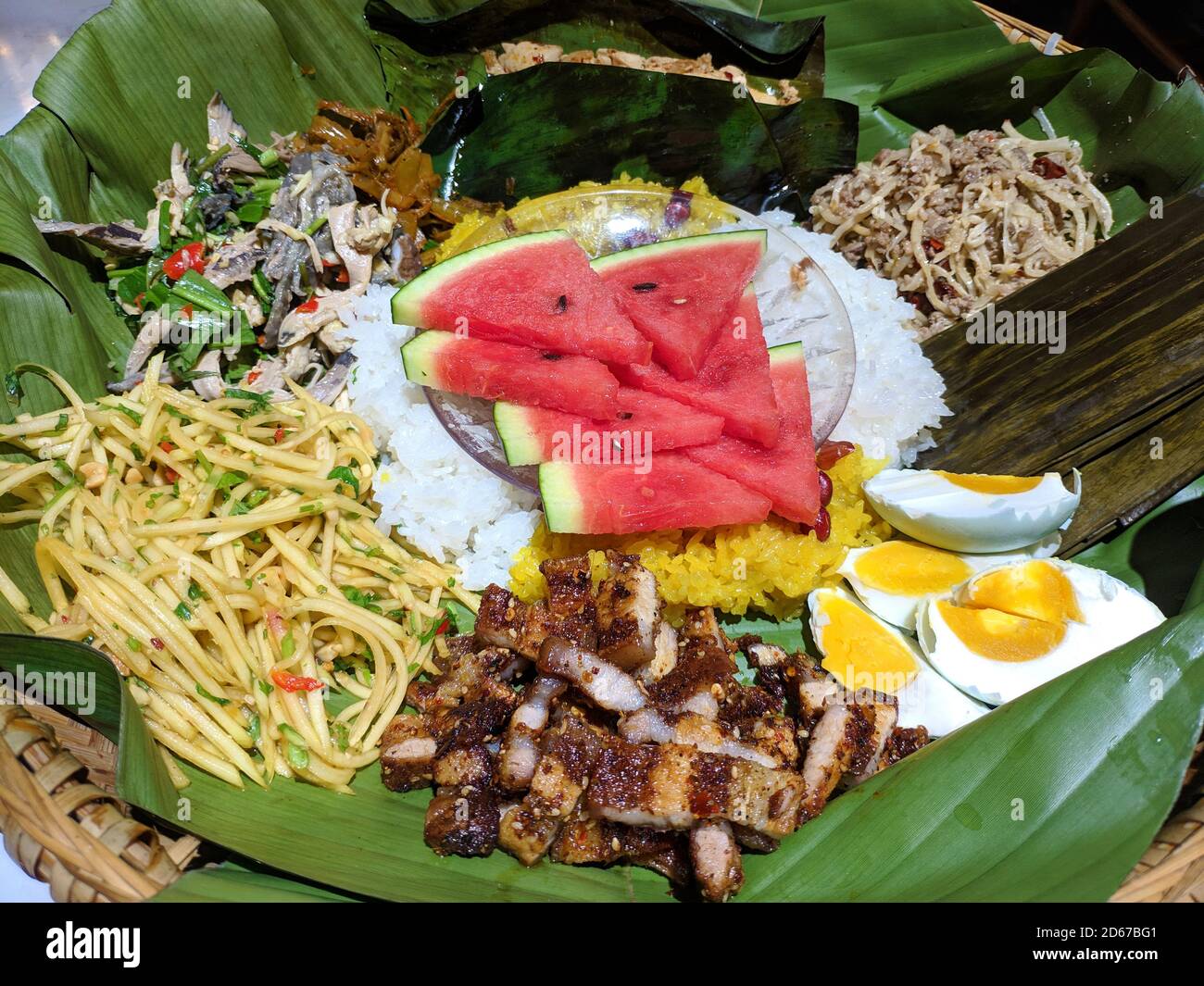 colorful cuisine and watermelon on the green leaves as plate for eating ...