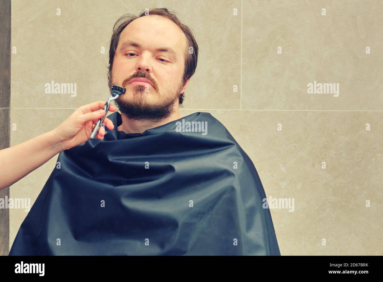 A woman's hand shaves a man's beard with a safety razor, copy spce ...