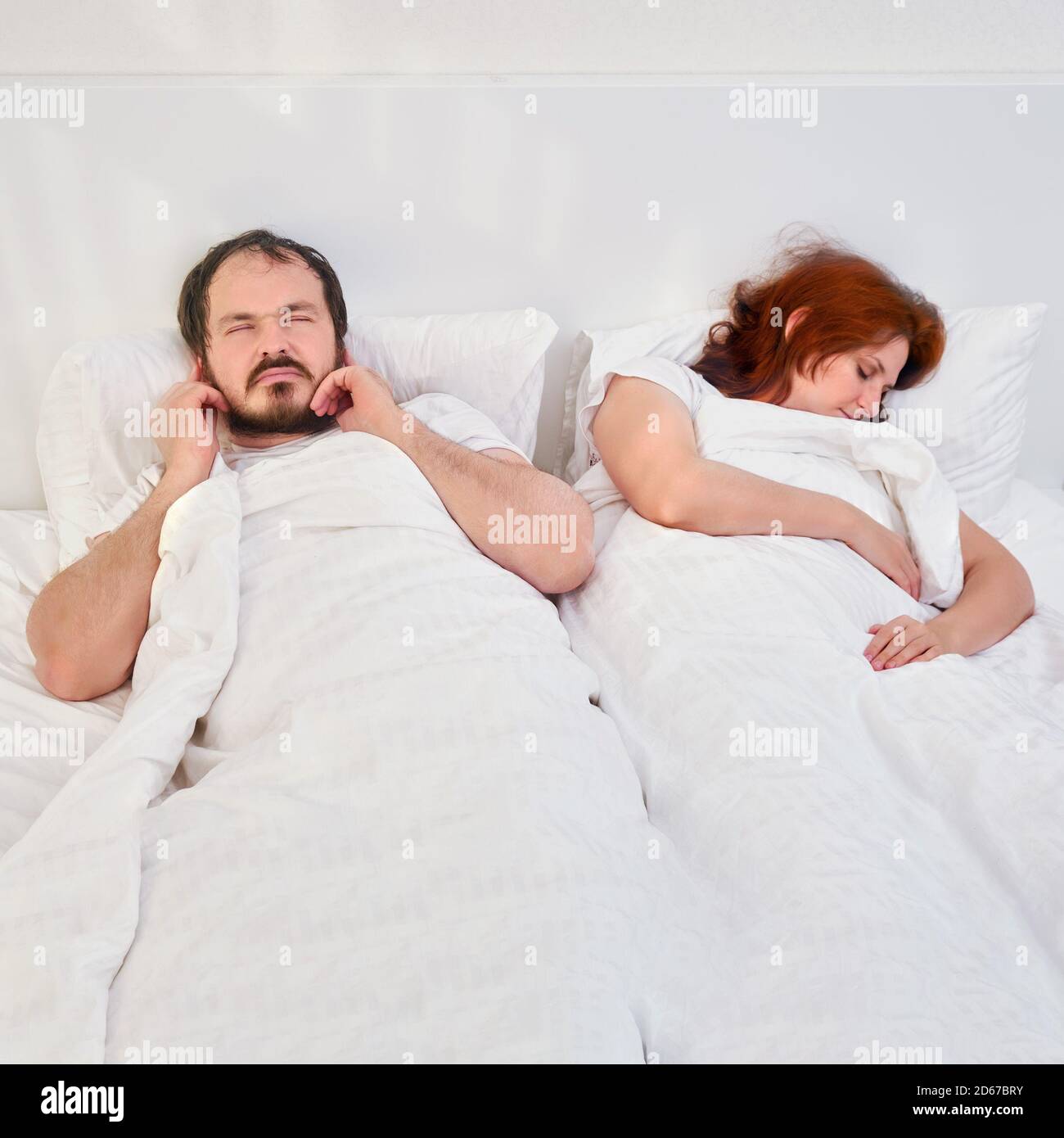 A man plugs his ears with earplugs because of the noise and snoring of ...