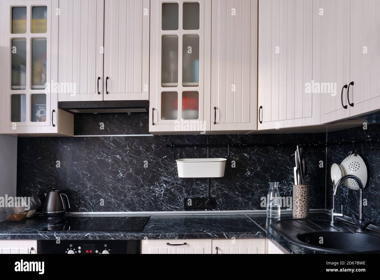 White wall cabinets in the kitchen with a black countertop. Placed ...