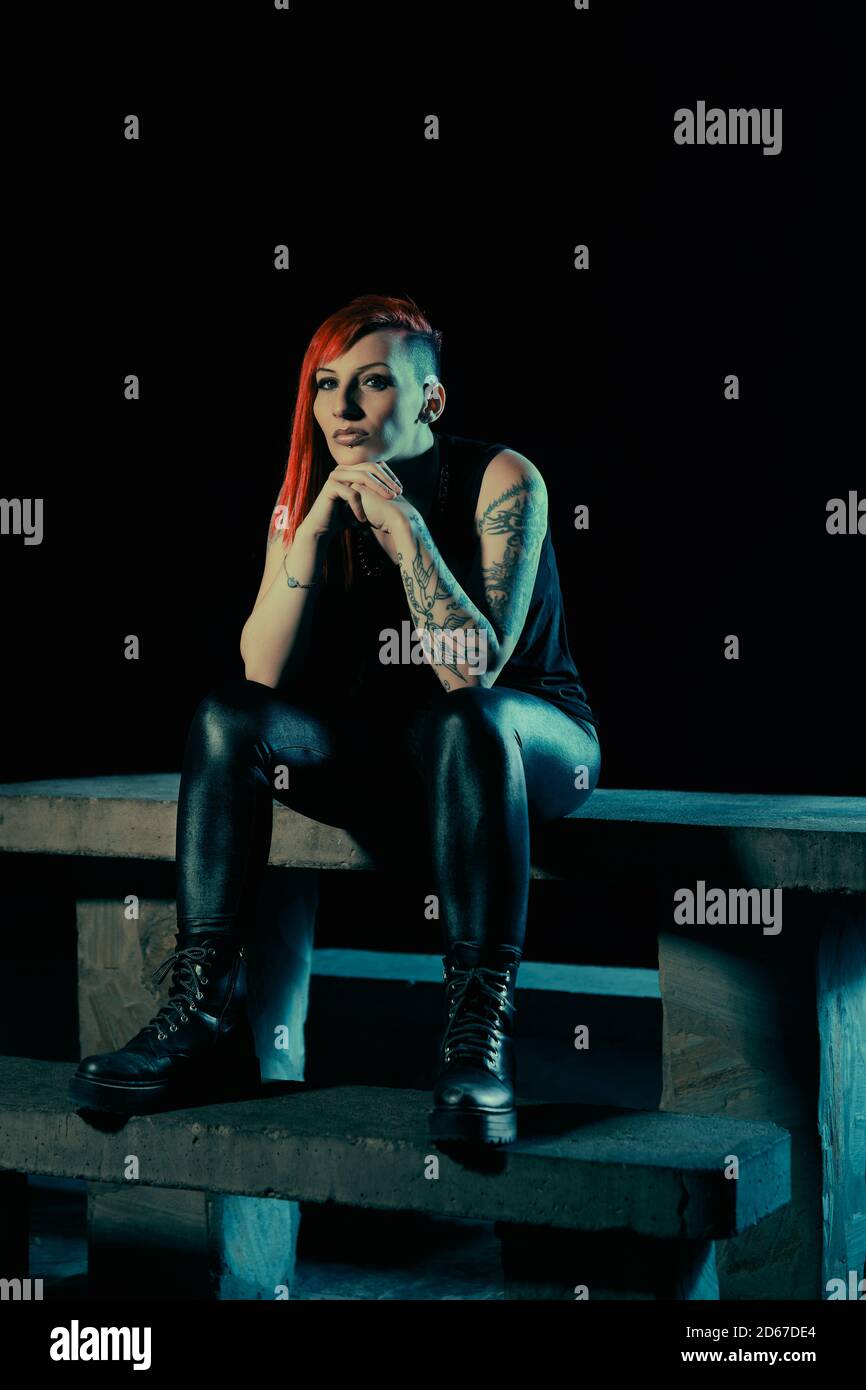 Revolutionary girl with defiant face and red hair sitting against dark ...