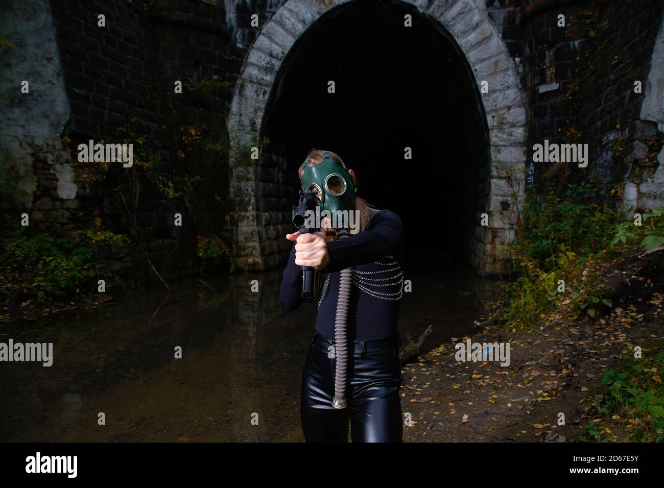 a woman in a black suit and gas mask with a machine gun in her hands ...