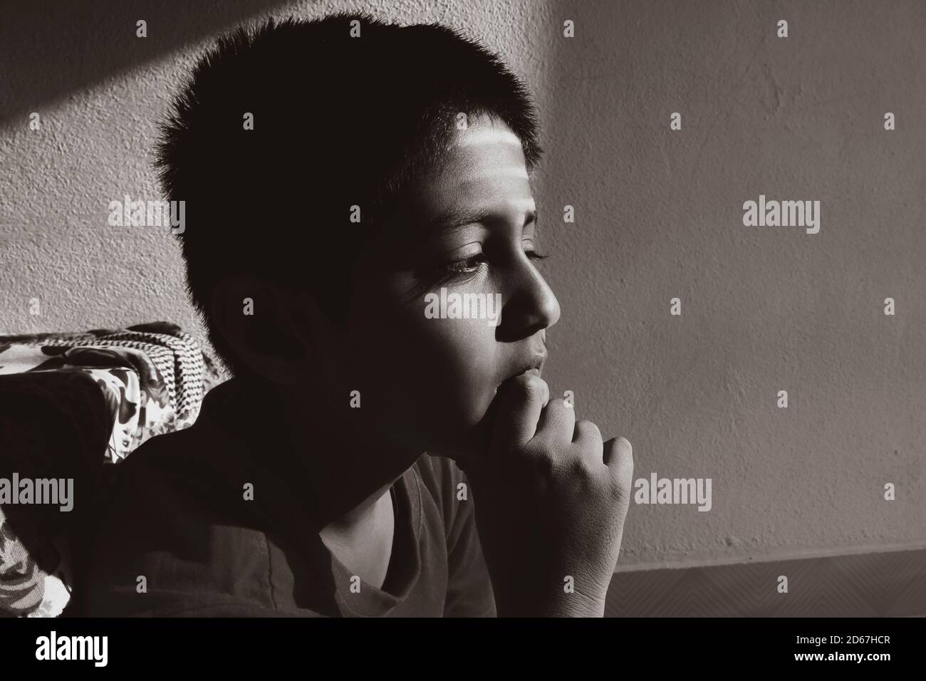 a close head shot of Indian boy thinking low key light in the morning ...