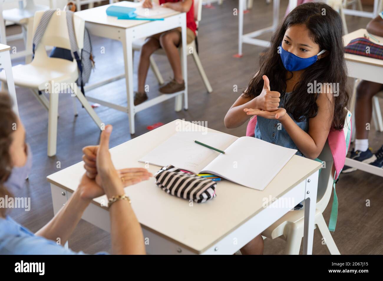 Female teacher and girl wearing face masks talking to each other ...