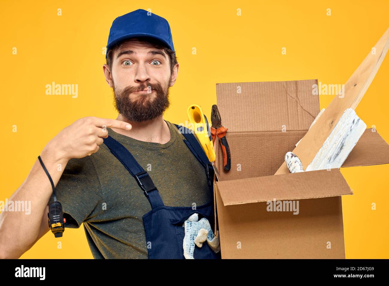 A man in a working form a box with loading tools yellow background ...