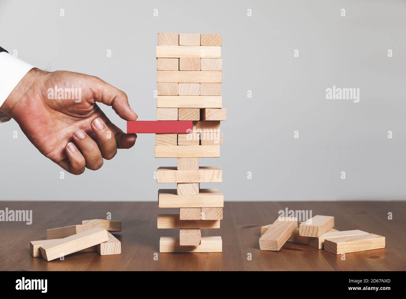 Human hand removing the wooden red block out of the wooden block tower ...