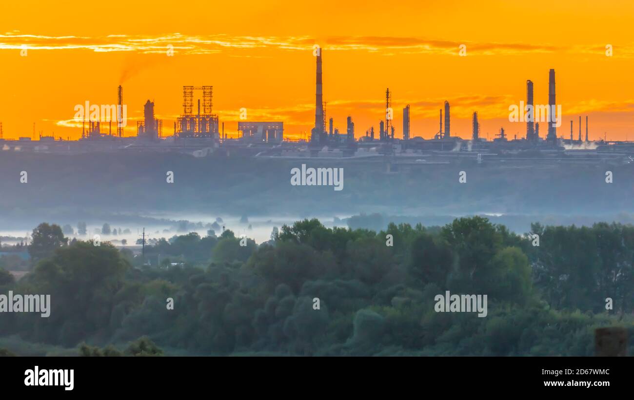 Scarlet sunrise over a chemical plant with pipes at the edge of a ...