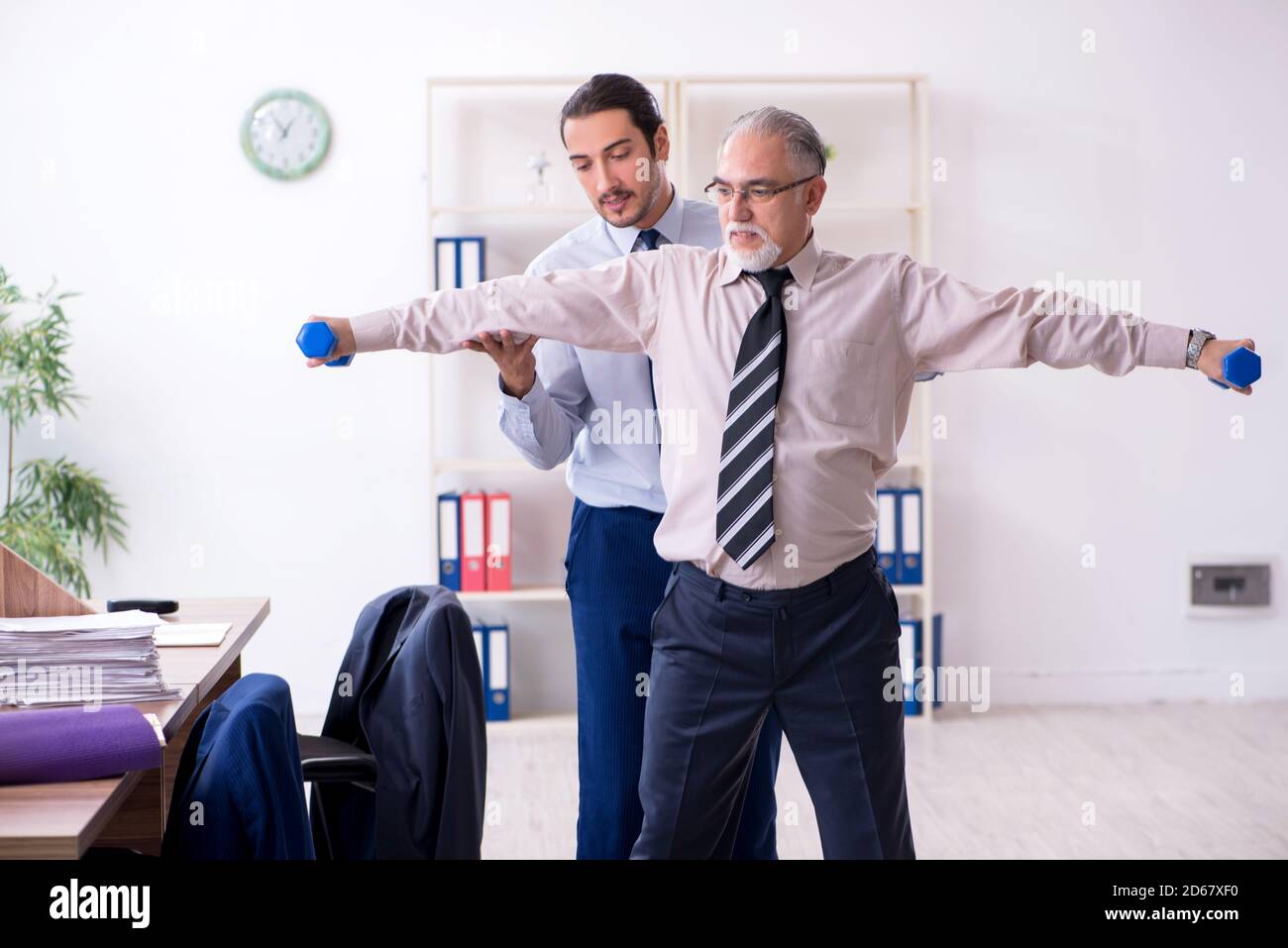 Two employees doing physical exercises at the workplace Stock Photo - Alamy