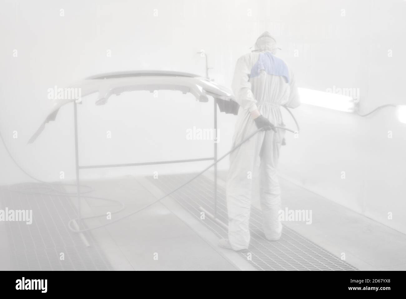 All in a haze of paint. Worker painting parts of the car in special ...