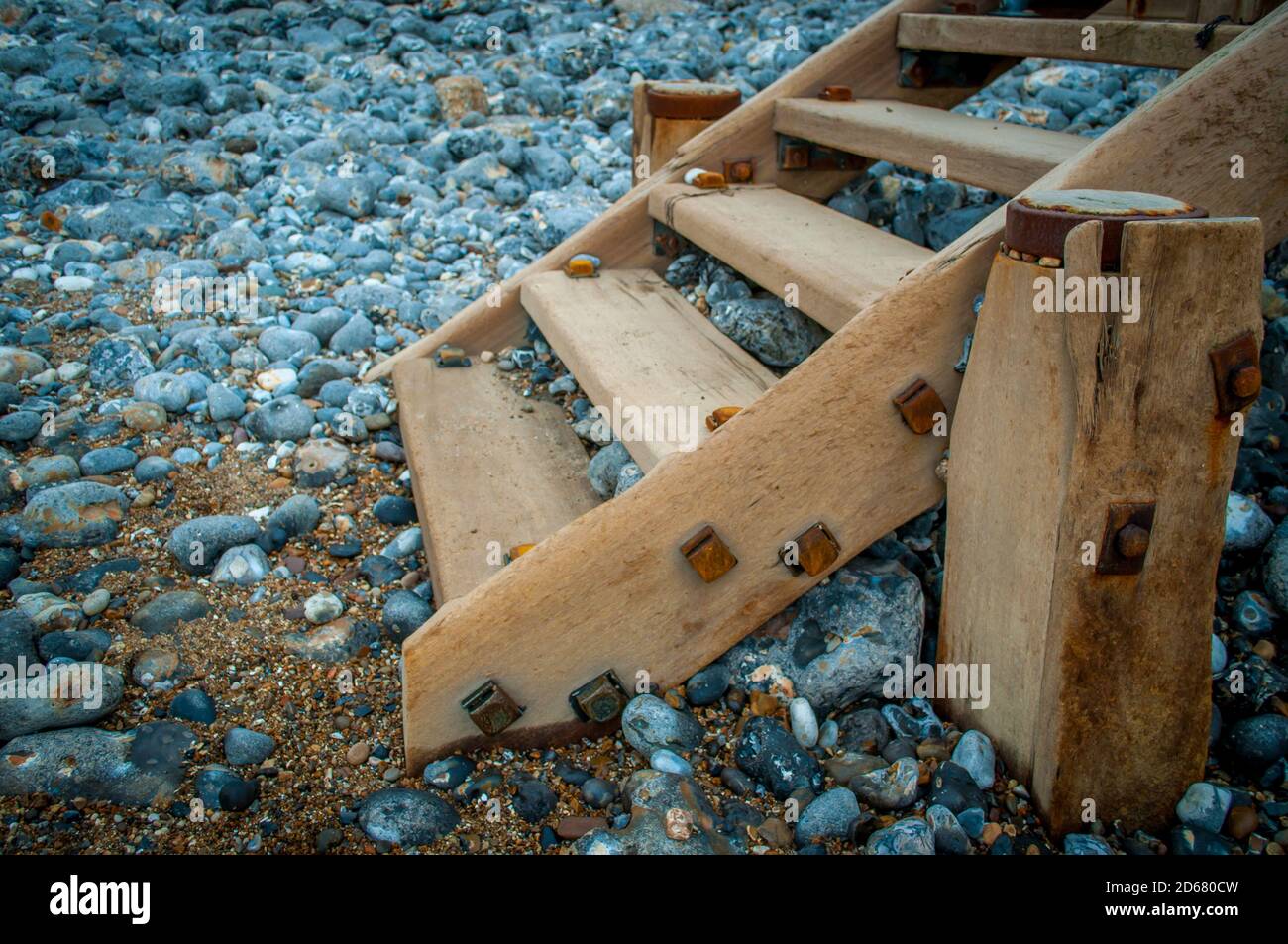 Weathered wooden steps lead up sideways on from a pebble beach in ...