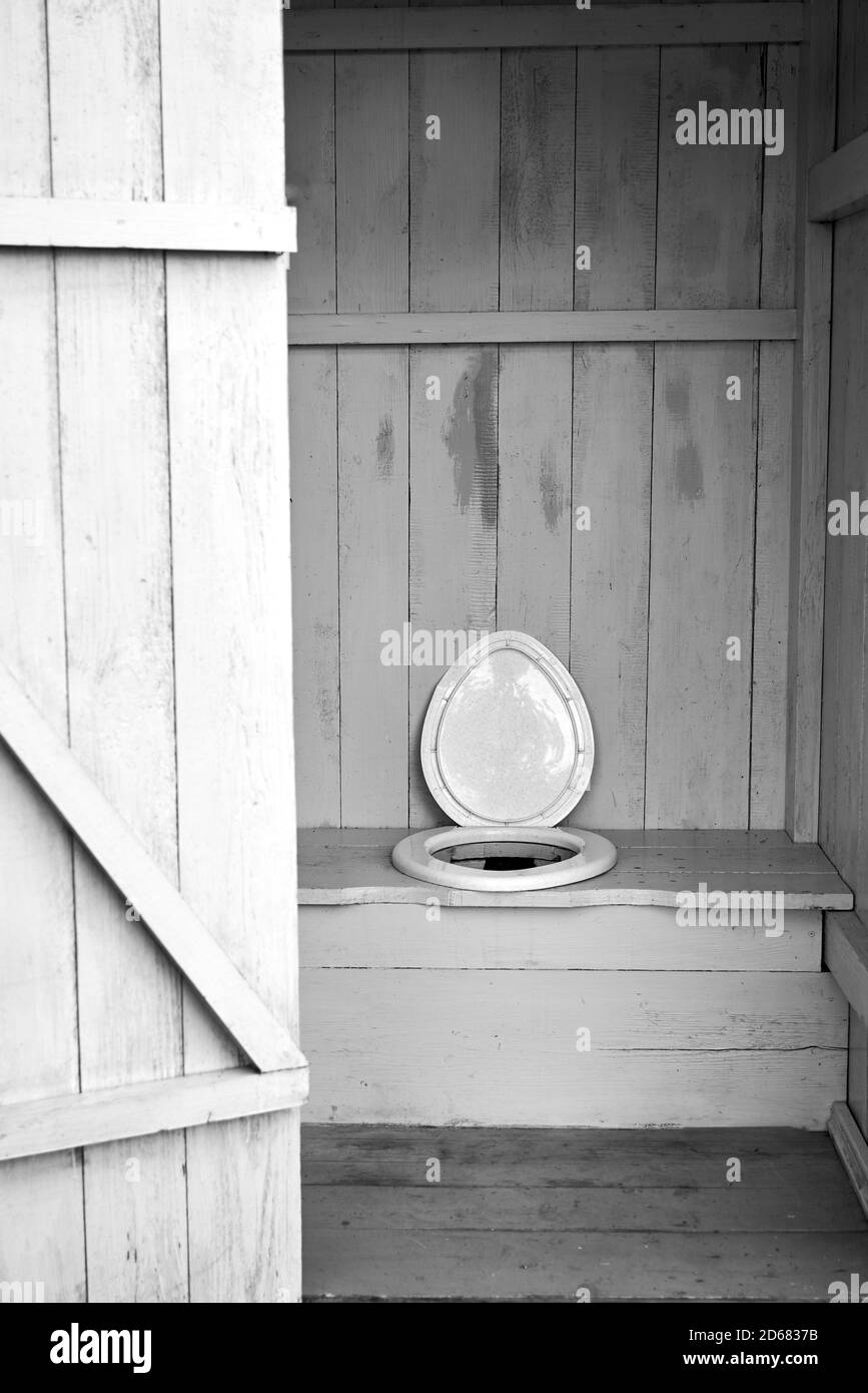 A simple clean rural toilet with a plastic seat in a wooden booth, life ...