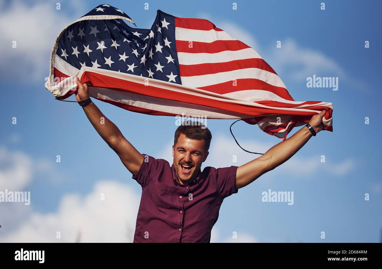 Patriotic happy man waving American Flag against cloudy blue sky Stock ...