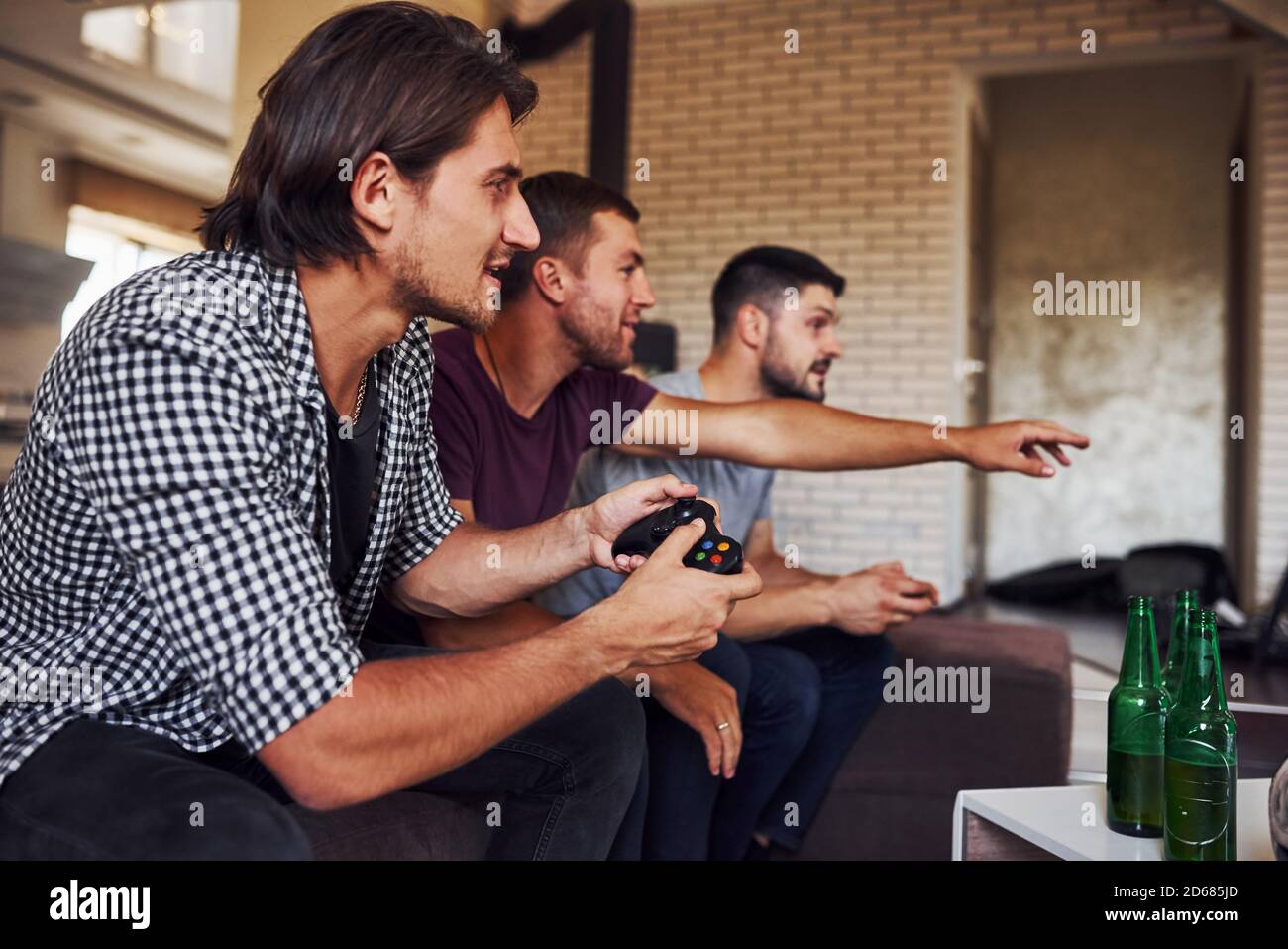 Side view. Group of friends have fun playing console game indoors at ...