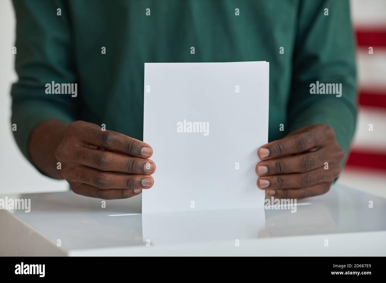 Close-up of Afro-American voter holding ballot standing near the ballot ...