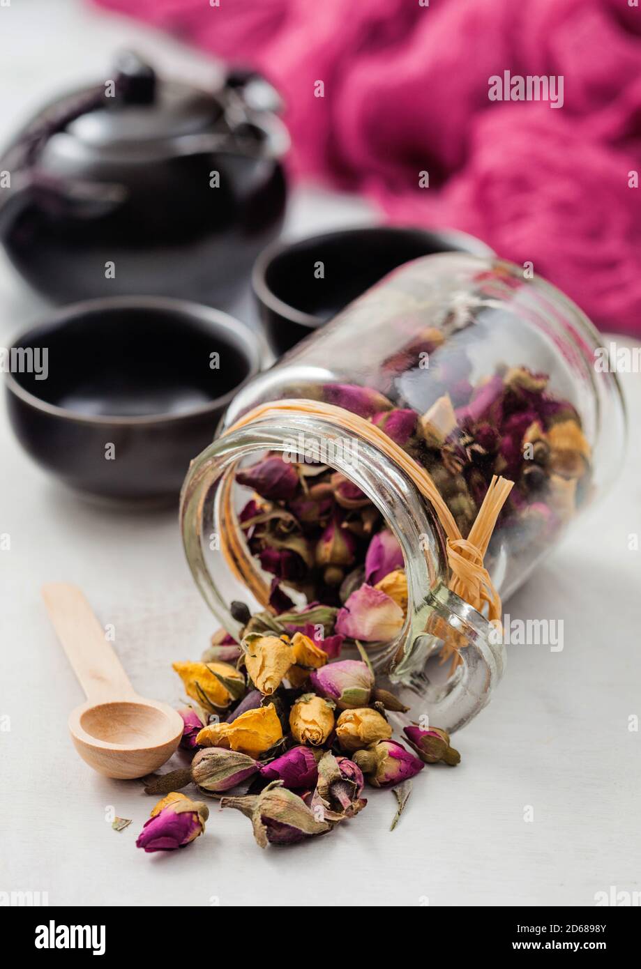 Glass jar of rose buds mix tea with wooden scoop on white background ...