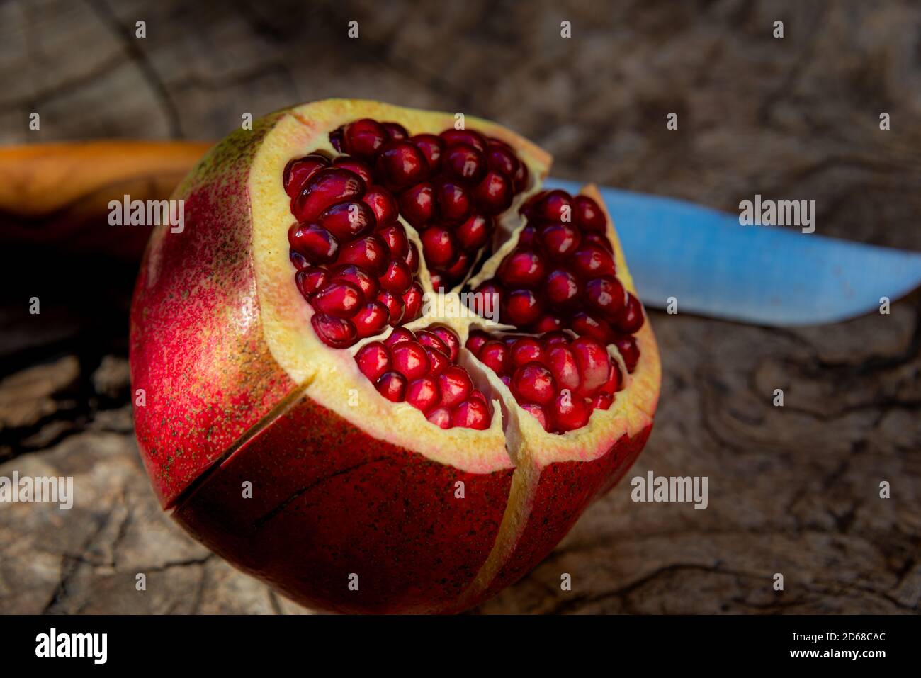 Cut open Pomegranate showing colouful seeds on rustic wooden table with ...