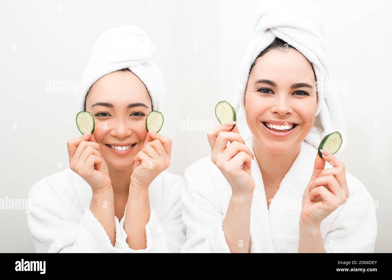 Use a cucumber to moisturize your face. Two beautiful women hold a ...