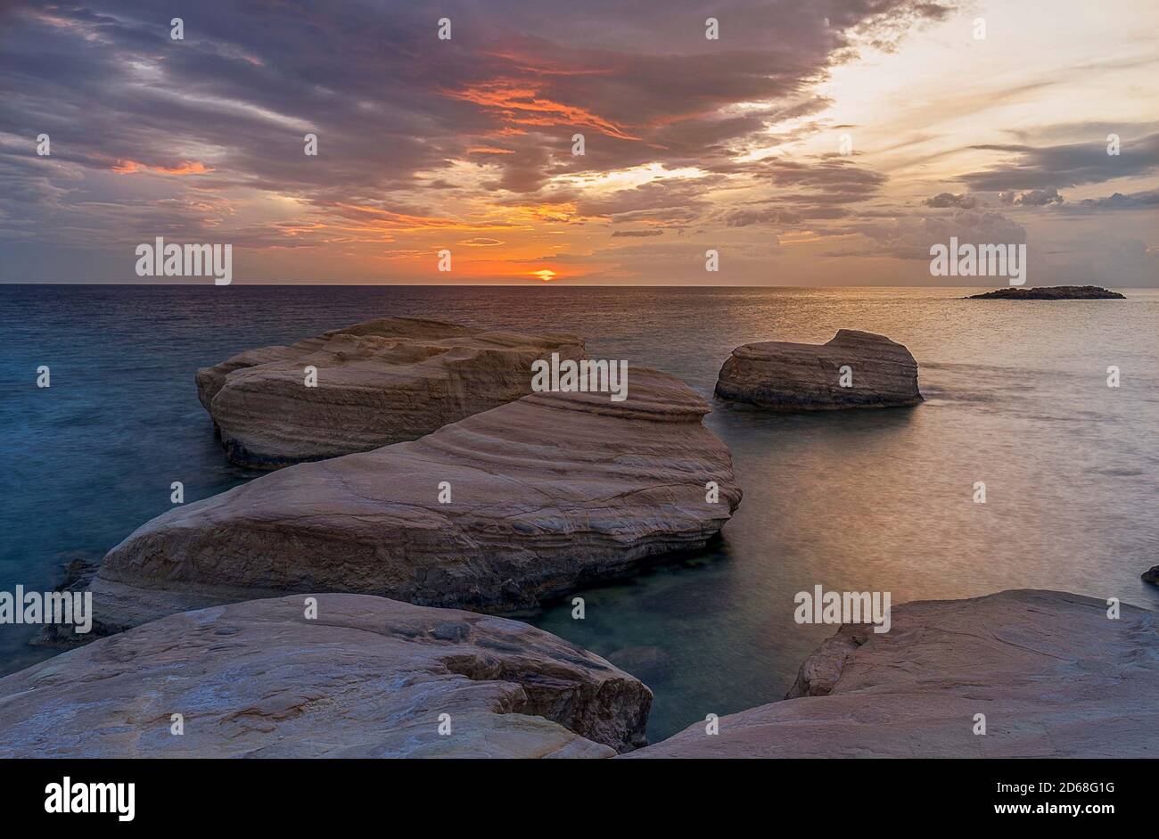 sunset over rock formation in sea Stock Photo - Alamy