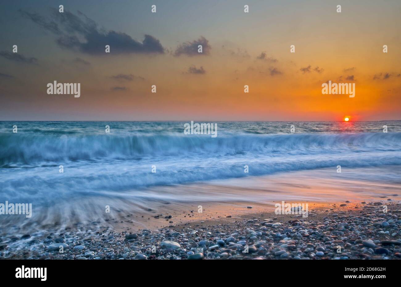 Long exposure of sunset and crashing surf on pebble beach Stock Photo ...