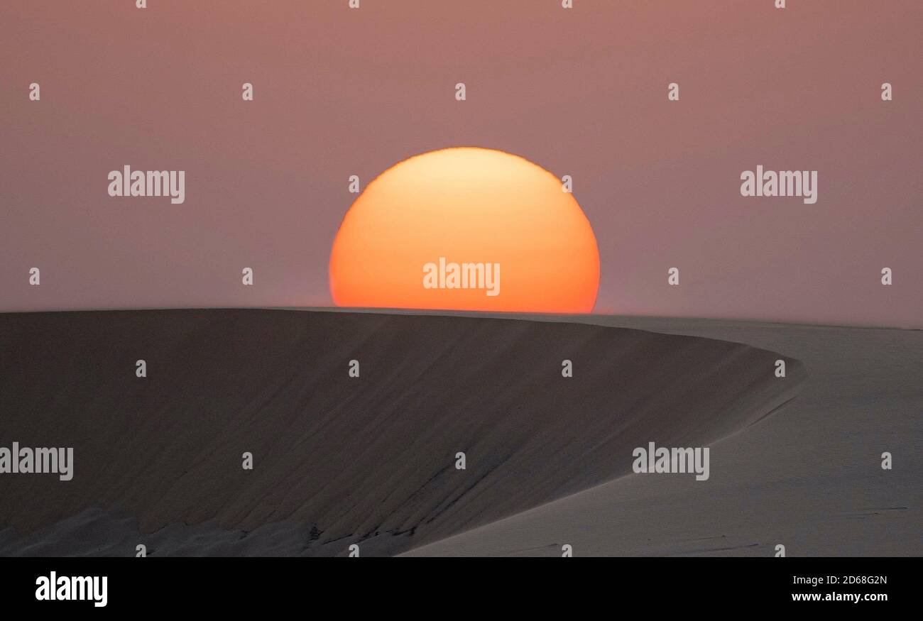 Telescopic sun setting over a desert sand dune with stunning colours ...
