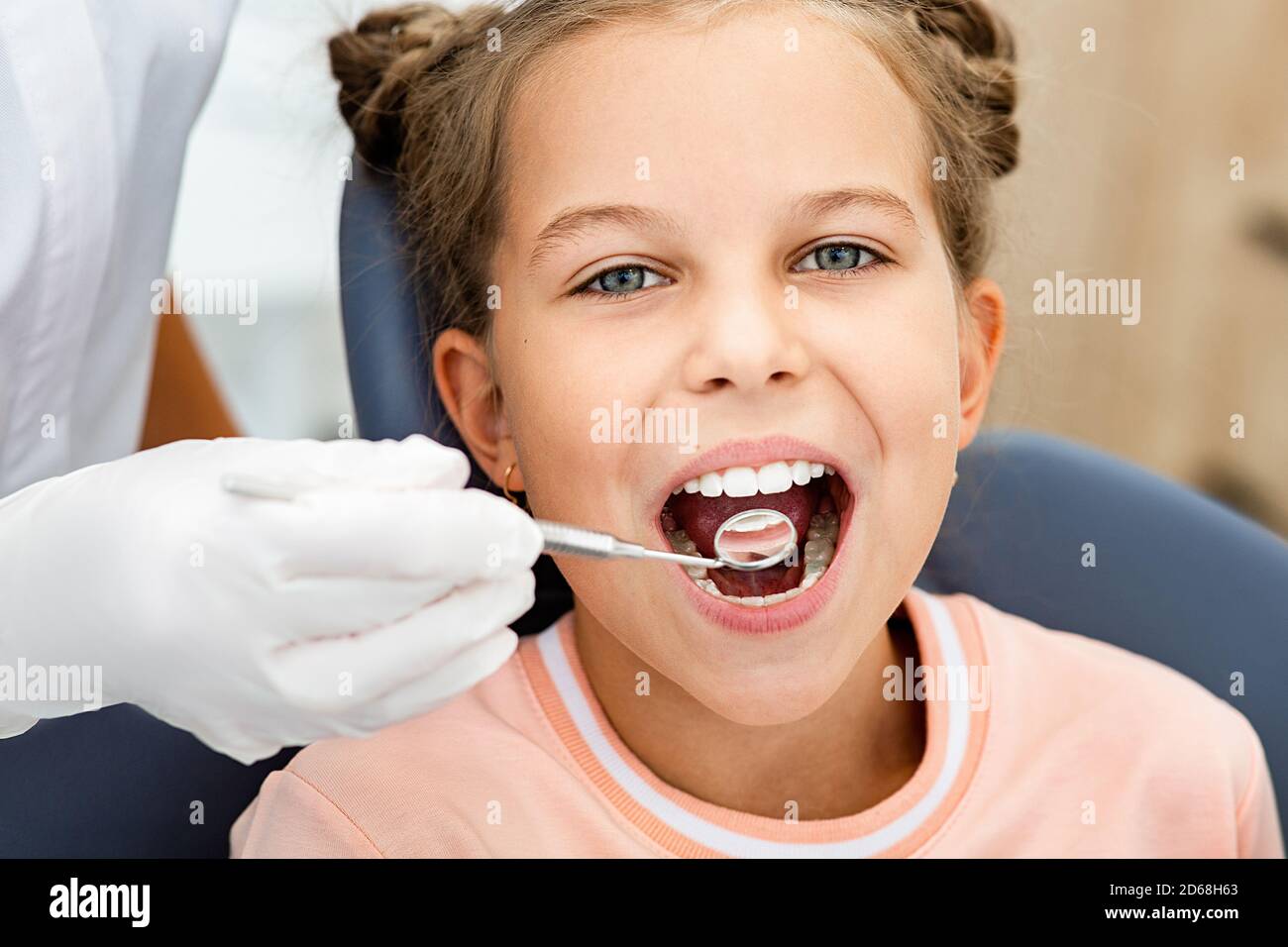 Little smiling girl, teeth check-up. Tooth exam using dental mirror ...