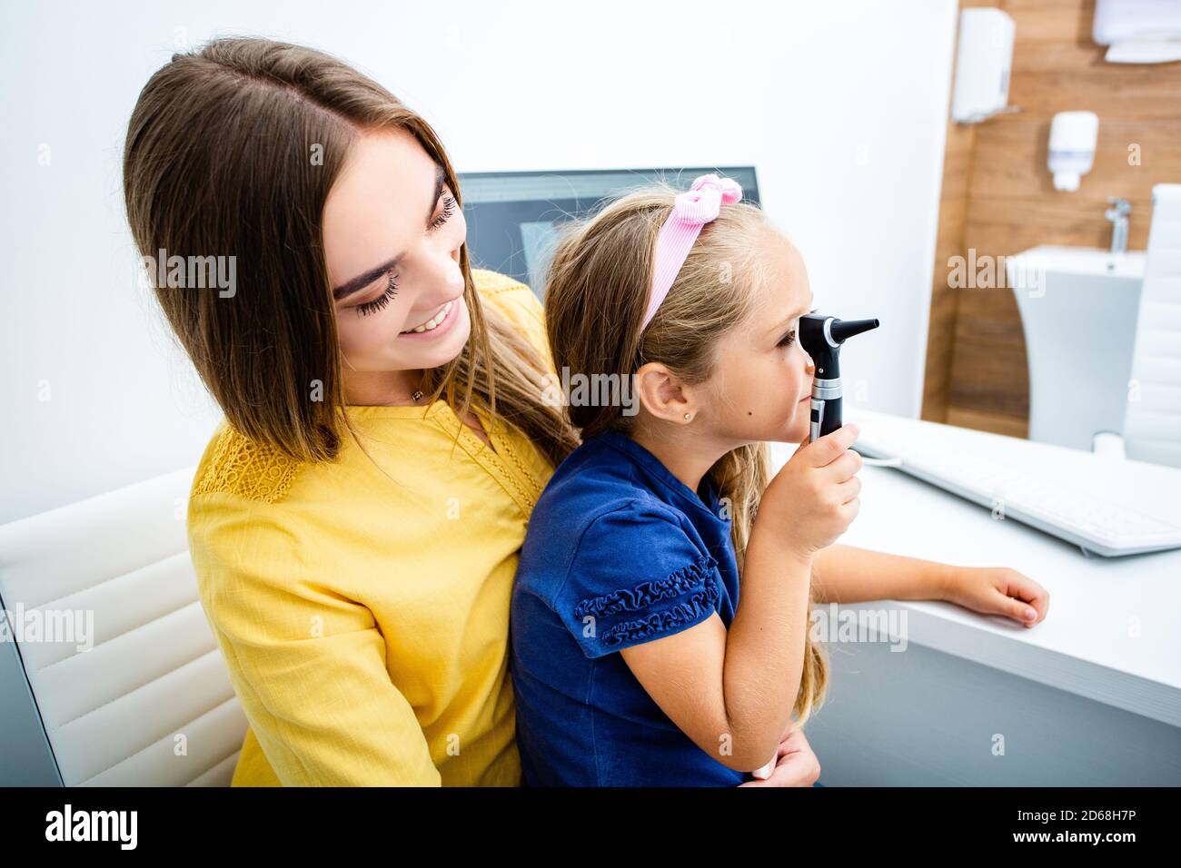 Portrait of a little girl who sitting in her mother's arms and looking ...