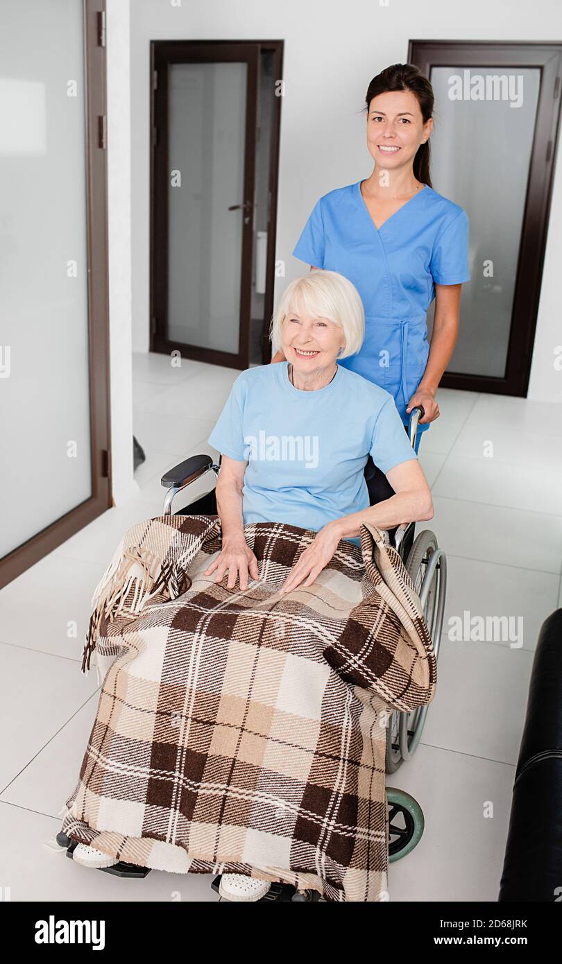 Smiling nurse and elderly woman patient in a wheelchair. Medical care ...