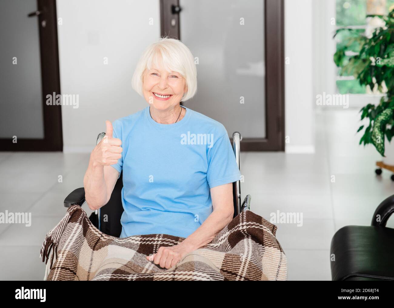 Elderly woman smiling while sitting in a wheelchair in a nursing home ...