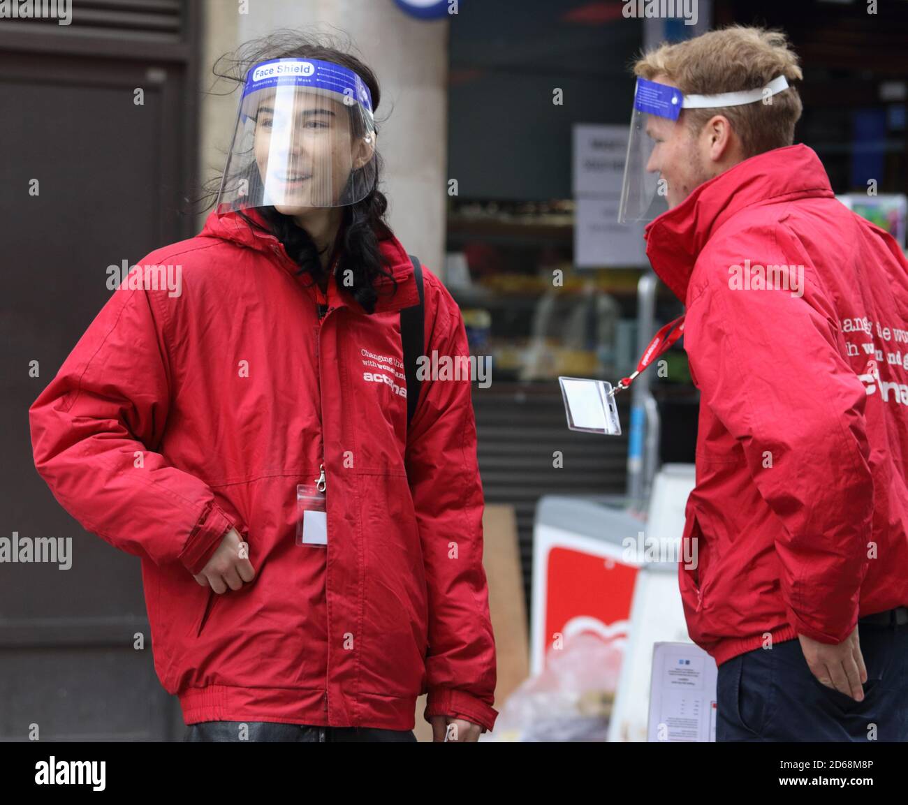 Two young charity collectors are seen wearing perspex face shields ...