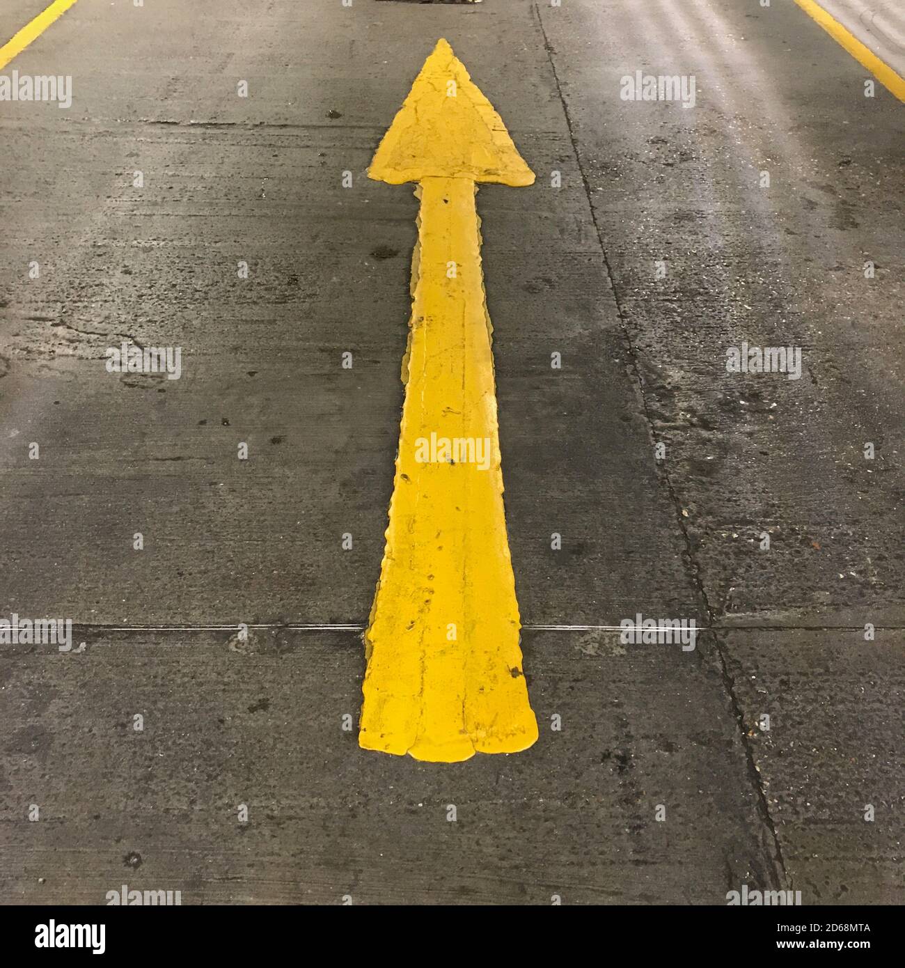 a Yellow arrow on the floor of a parking lot Stock Photo - Alamy